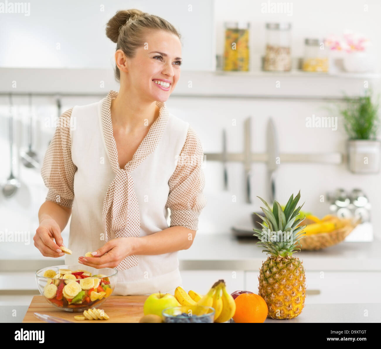 Happy young housewife making fruits salad Stock Photo - Alamy