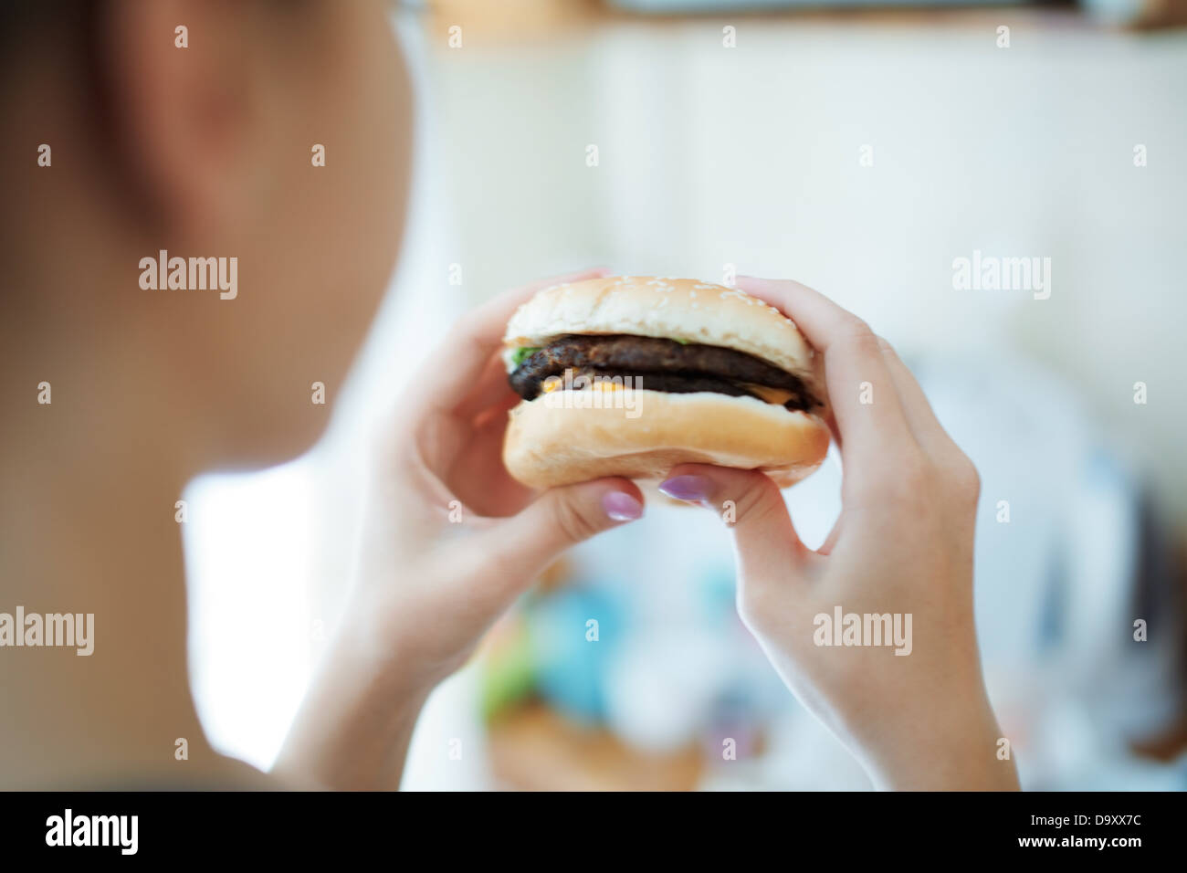 Woman eating hamburger. Rear view Stock Photo - Alamy