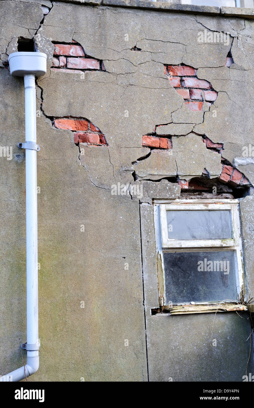 Cement rendering in a poor state of repair on brick wall and rotting ...