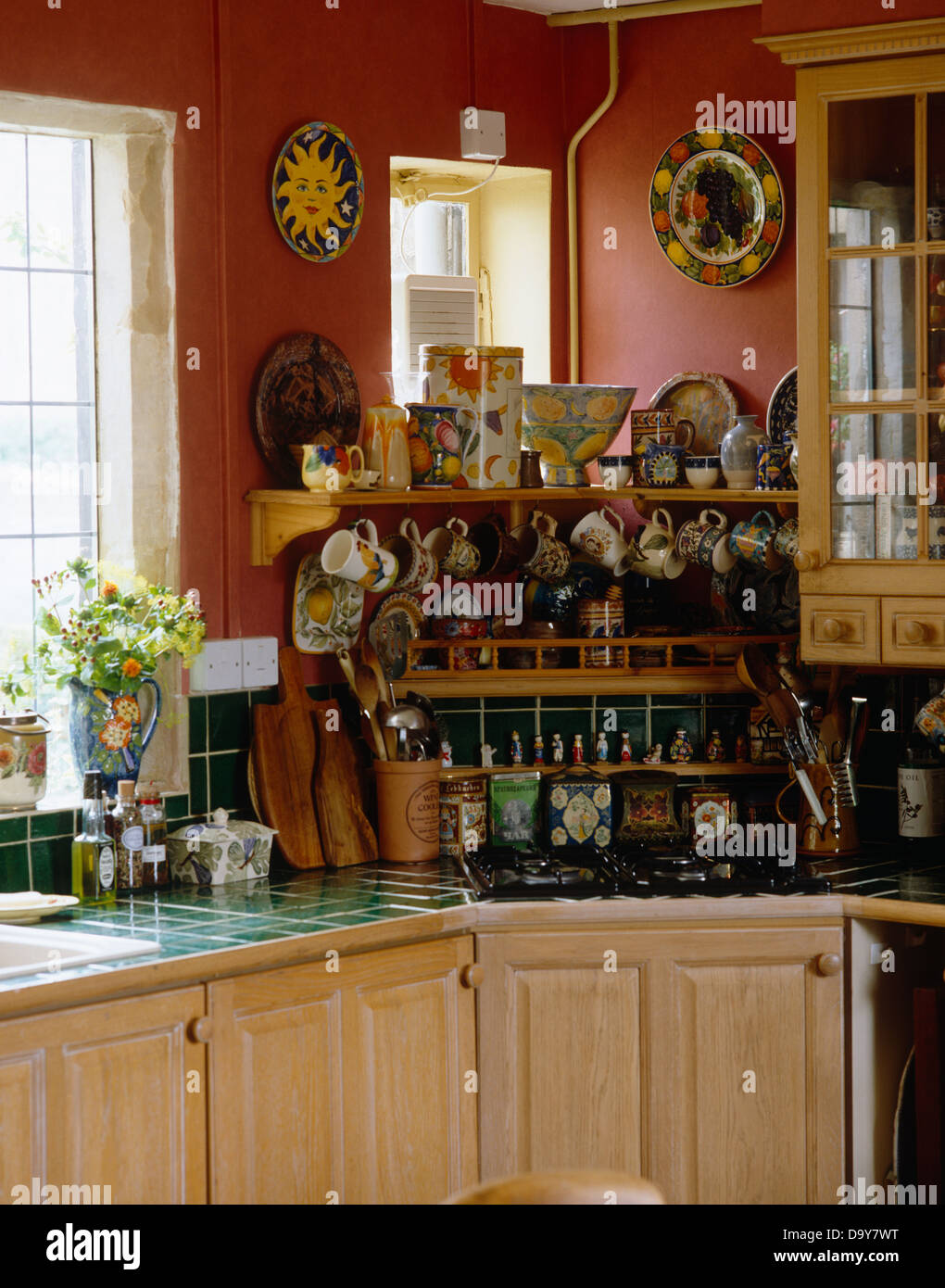 Display of pottery and tableware on pine shelf in red cottage kitchen ...