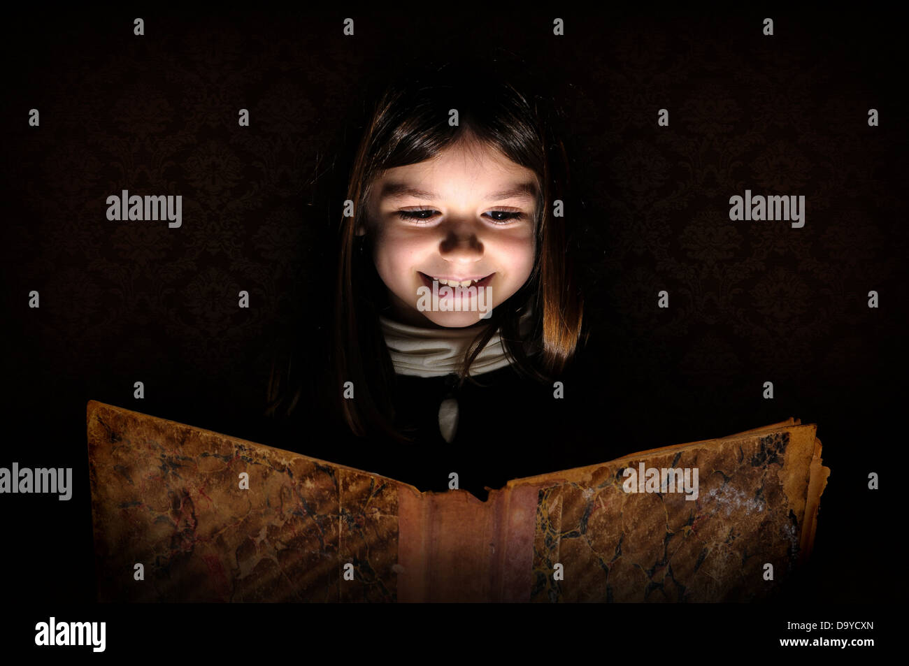 Young girl reading a very old book isolated in black Stock Photo - Alamy