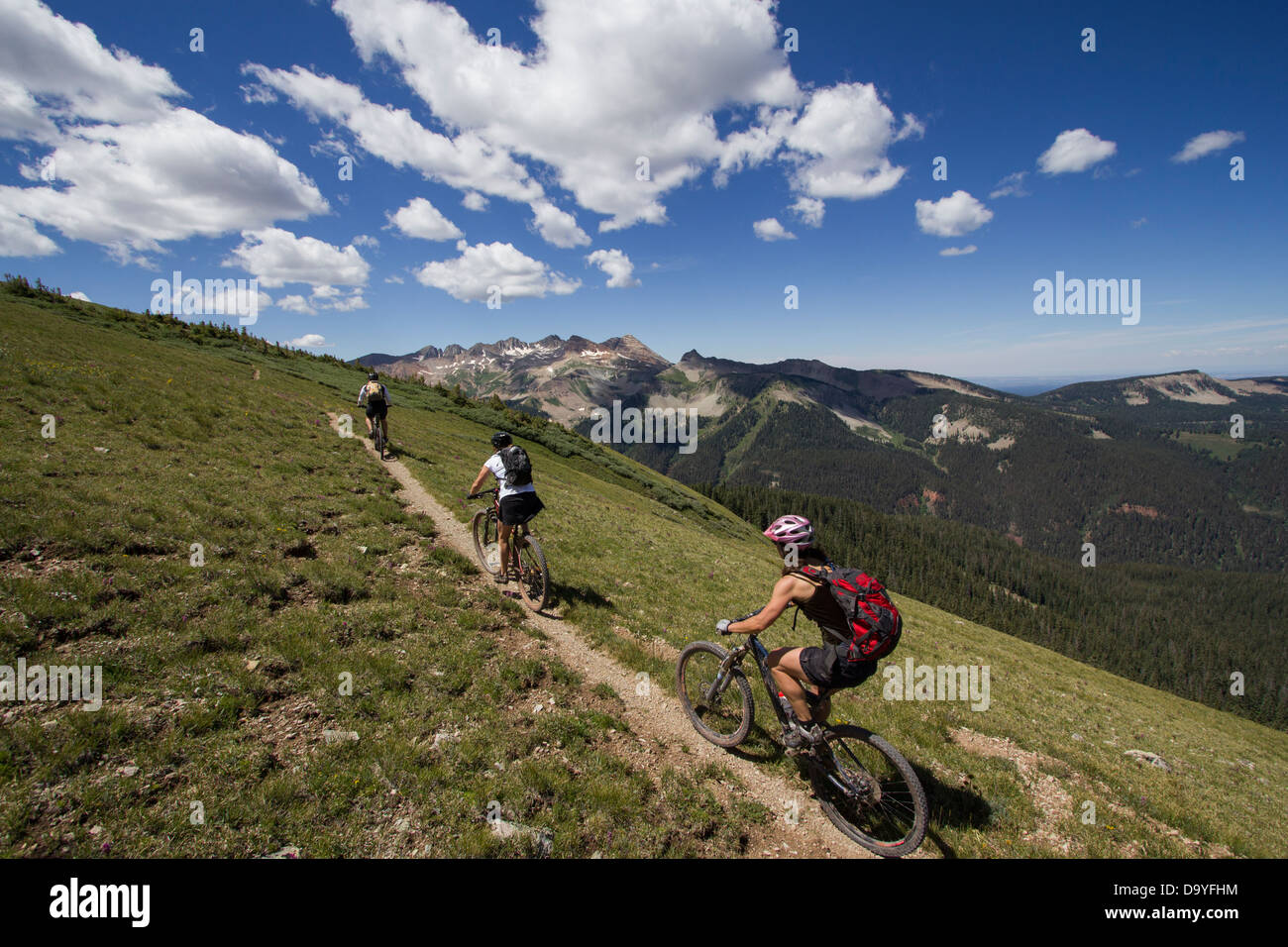 Three mountain bikers riding on a trail through the mountains Stock ...