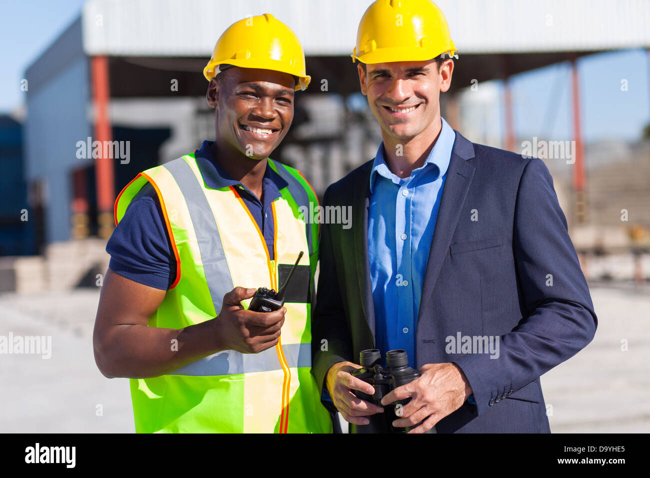 cheerful African construction worker and manager portrait outdoors ...