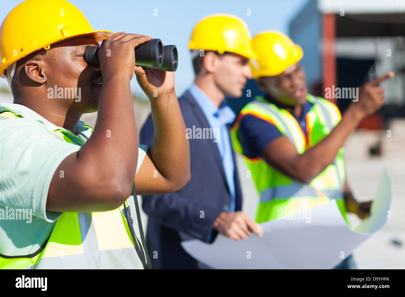 African construction worker using binoculars looking at construction ...