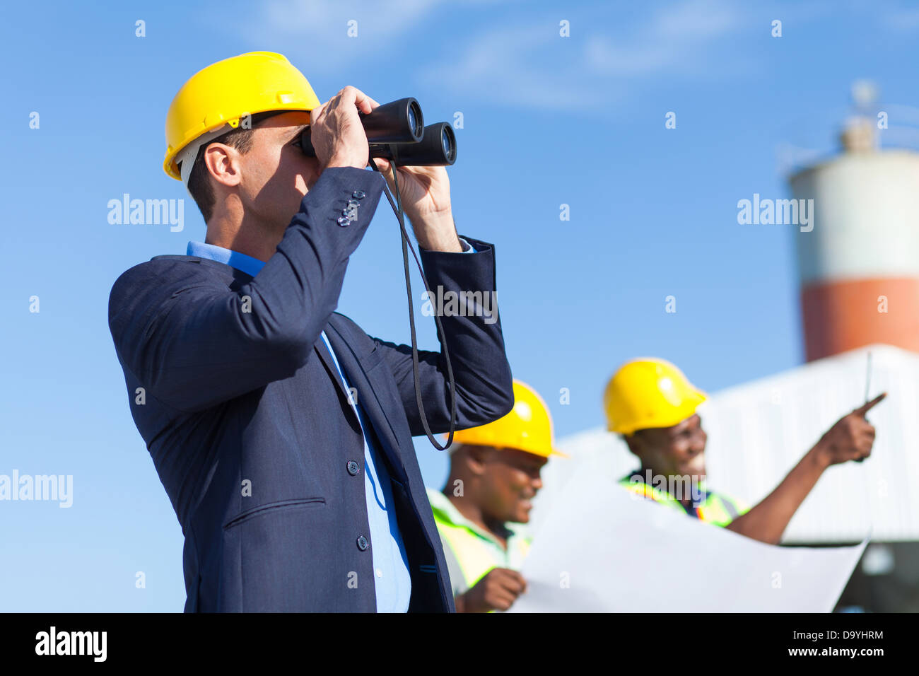 architect using binoculars looking at construction site with ...