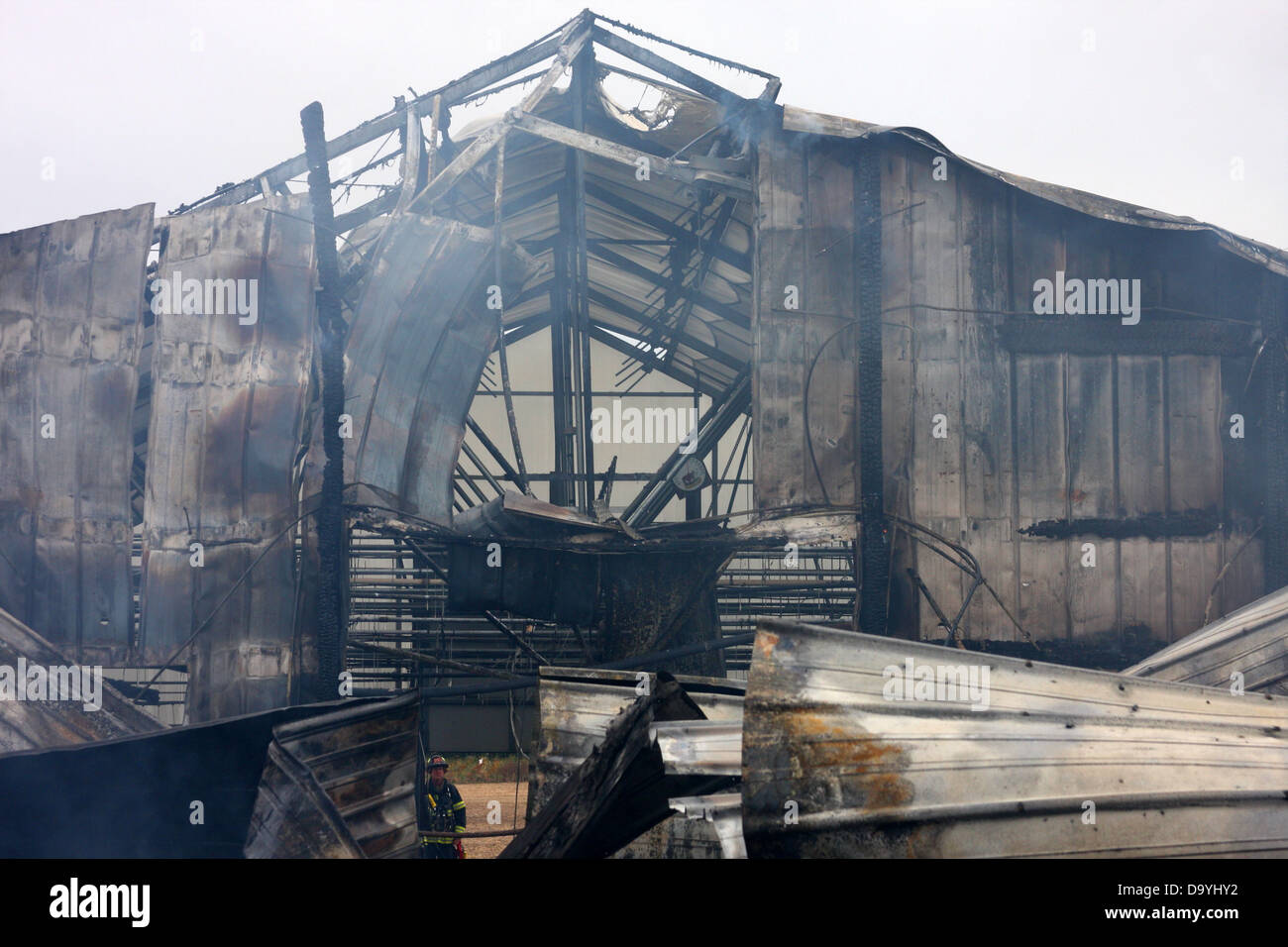A firefighter standing in a doorway of a massive burnt structure that ...