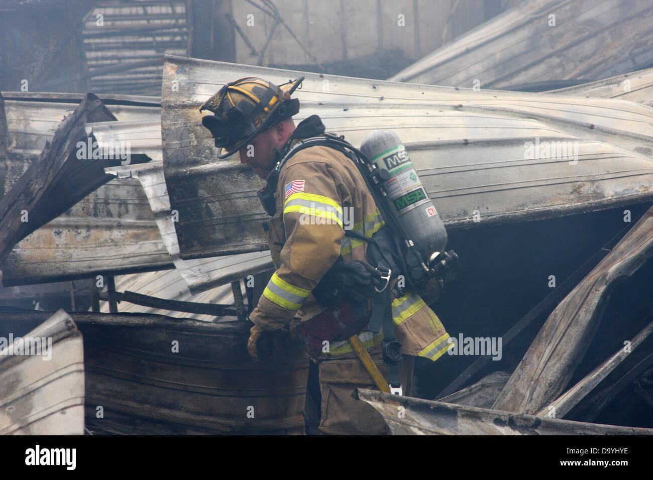 A firefighter digging through debris from a collapsed burnt building ...