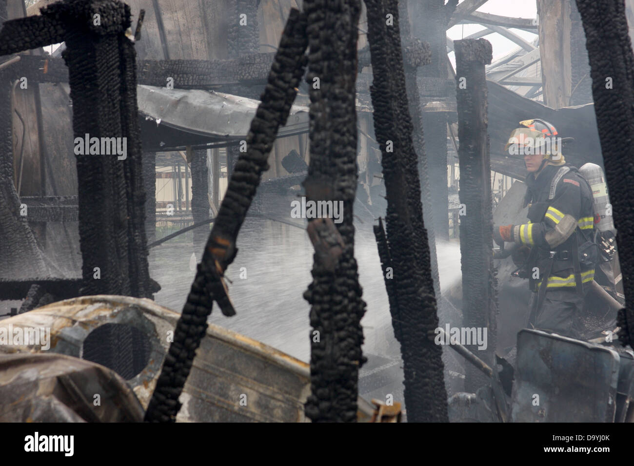 A firefighter pouring water on a structure fire hot spot Stock Photo ...