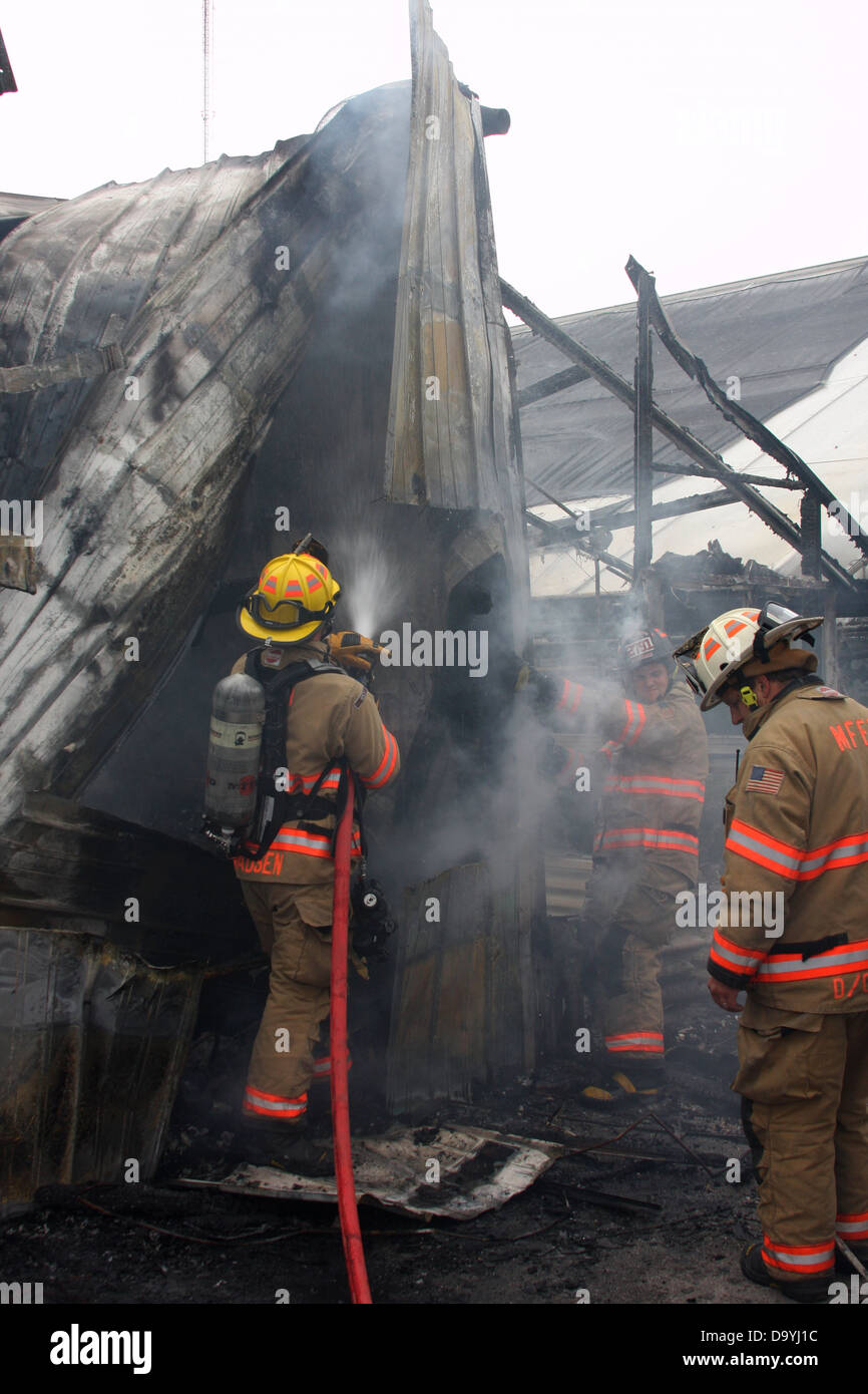 Firefighters extinguishing hot spots of flames in a collapsed building ...