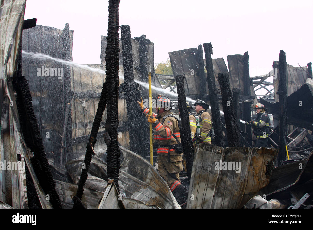 Firefighters working a scene to douse a fire in a collapsed building ...