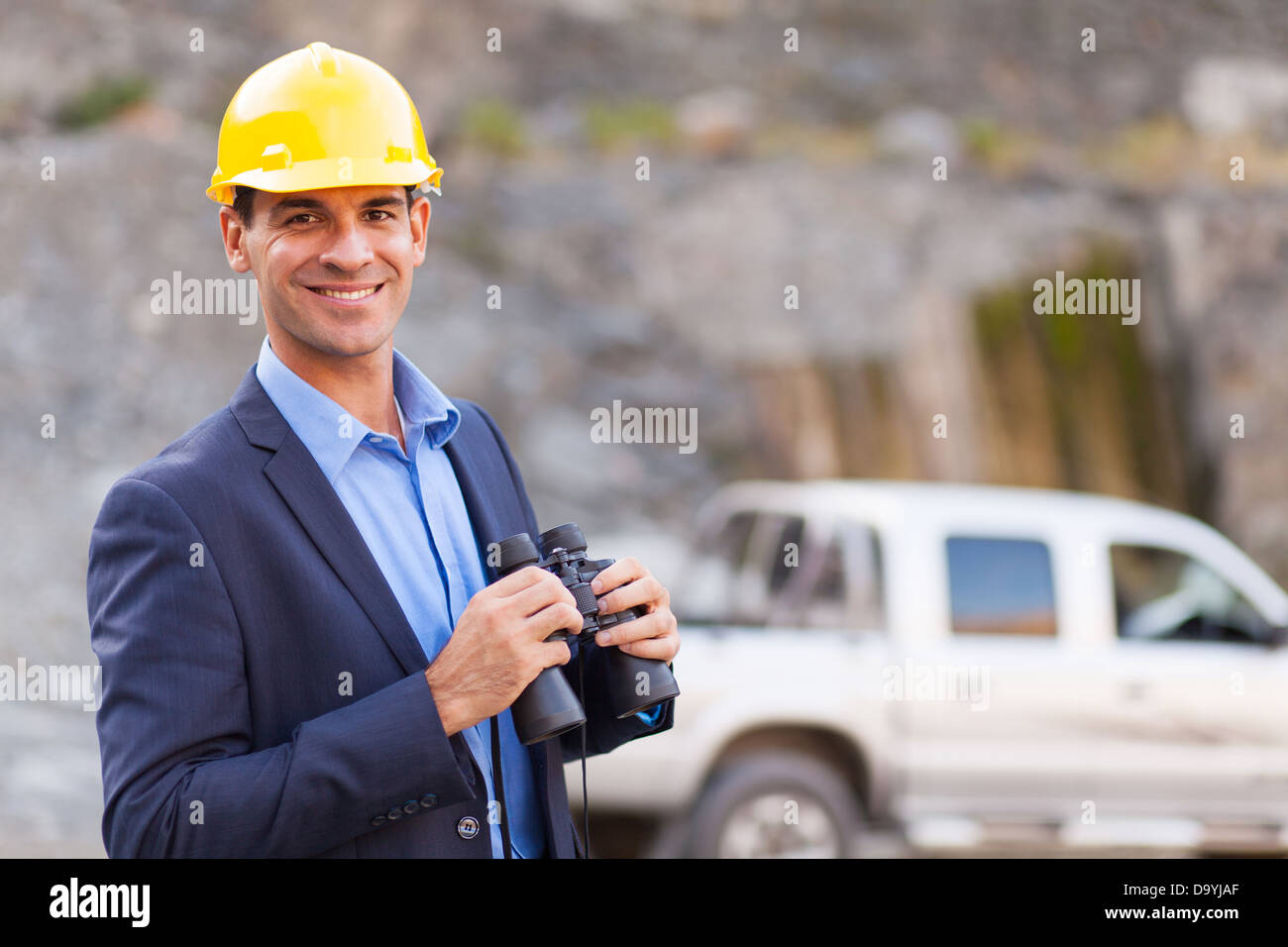 portrait of smiling mine manager with binoculars visiting mining site ...
