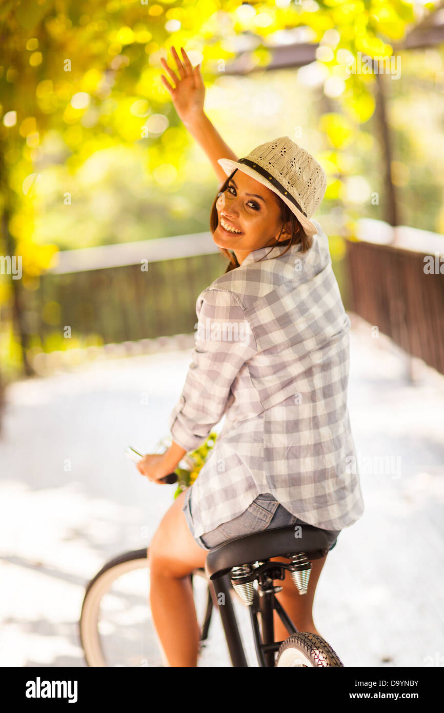 cheerful young woman riding her bike waving goodbye Stock Photo - Alamy