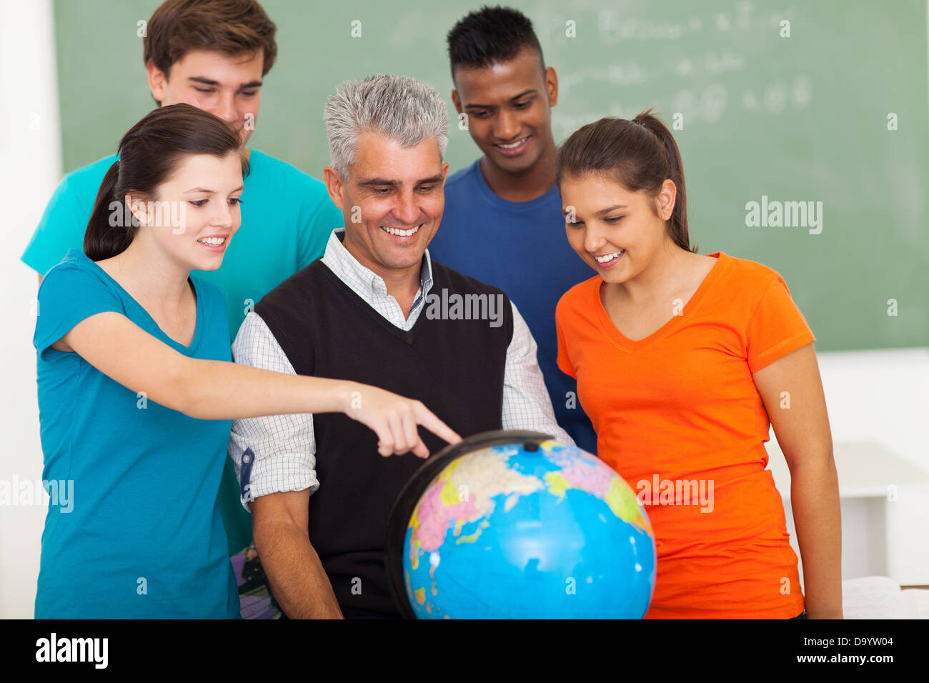 group of happy high school students and teacher looking at globe Stock ...