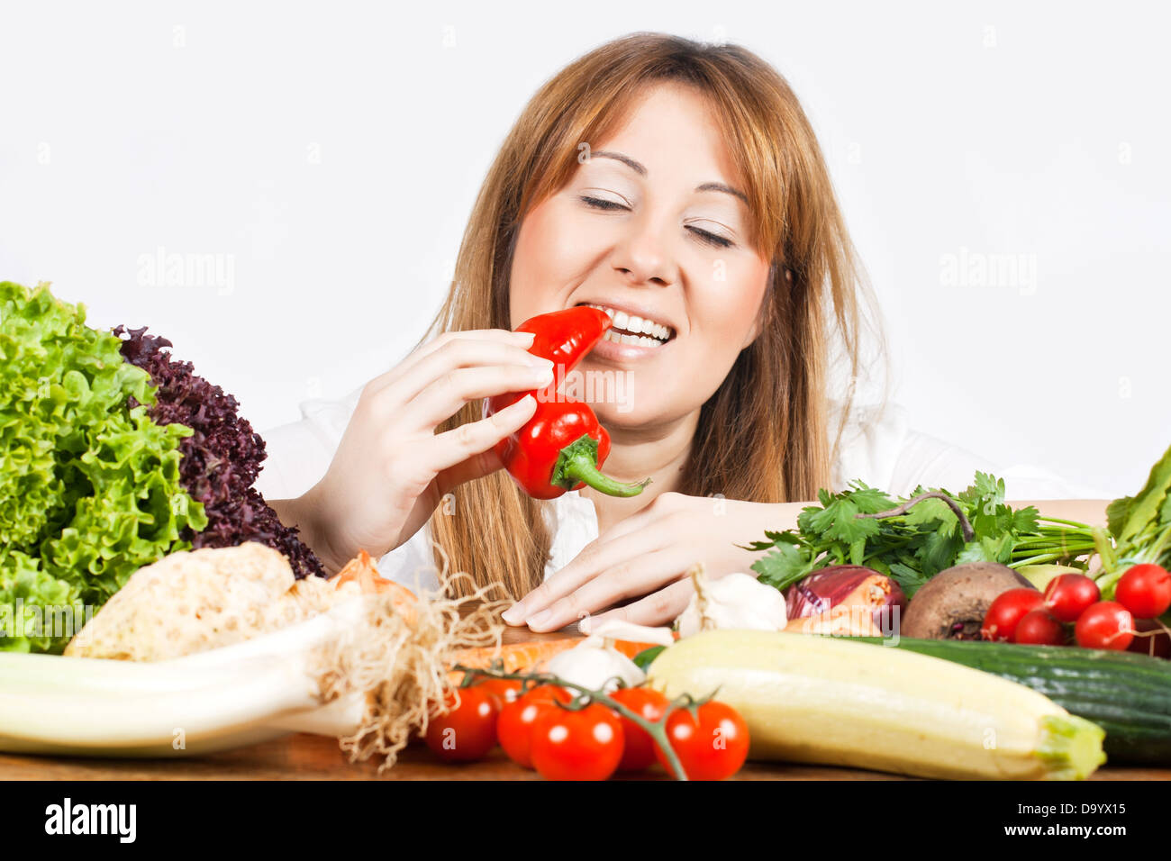 Young woman eating red pepper with mixed vegetable on table Stock Photo ...