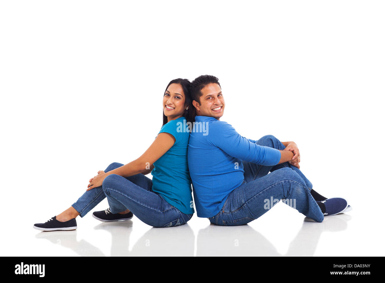 cheerful young indian couple sitting back to back on floor Stock Photo ...