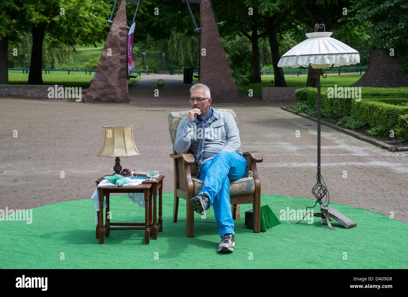 Adult man thinking and sitting on chair in a park with table and lamp ...