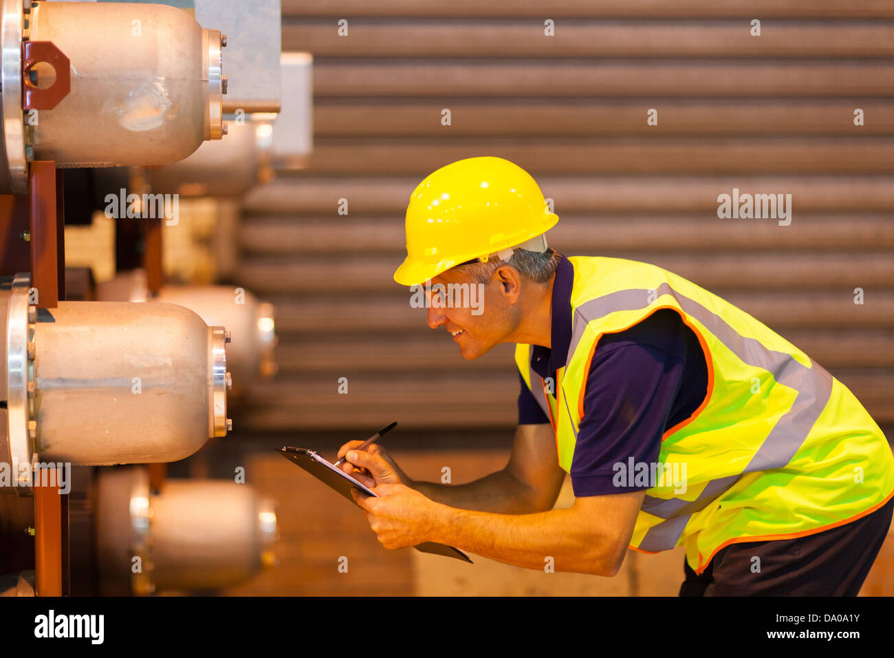 smiling senior shipping worker inspecting machinery at warehouse Stock ...