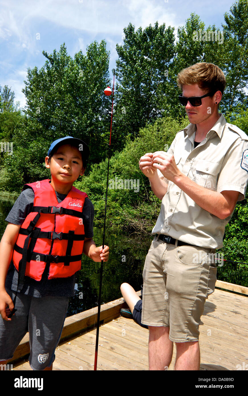 Freshwater Fisheries Society BC volunteer helping young Asian boy Learn ...