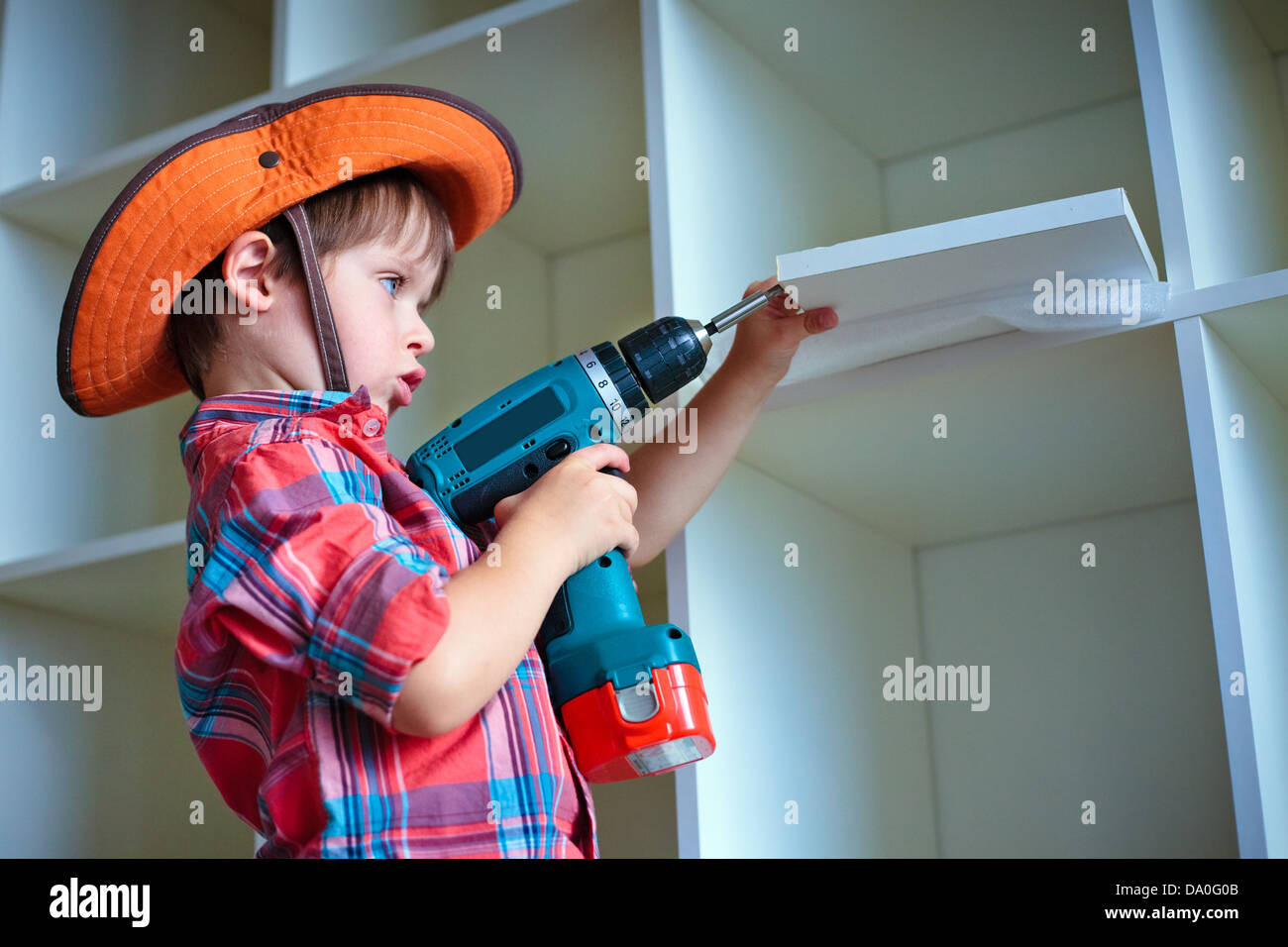 Cute little boy using an electric screwdriver Stock Photo - Alamy