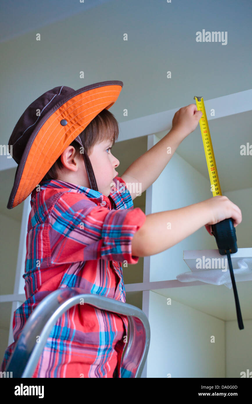 Cute little boy measuring a part of cupboard Stock Photo - Alamy