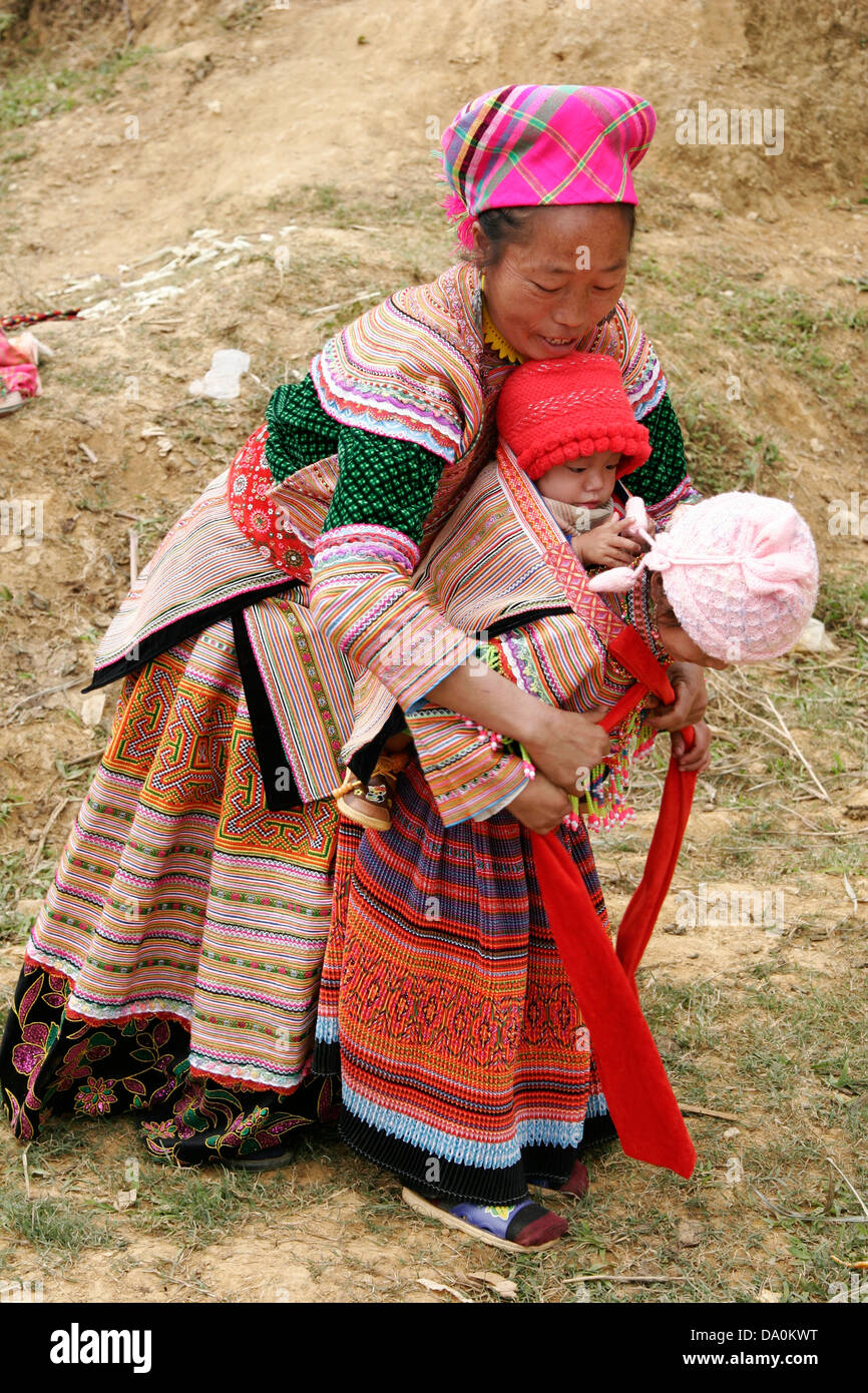 Flower Hmong woman helping her daughter to get her brother on the back ...