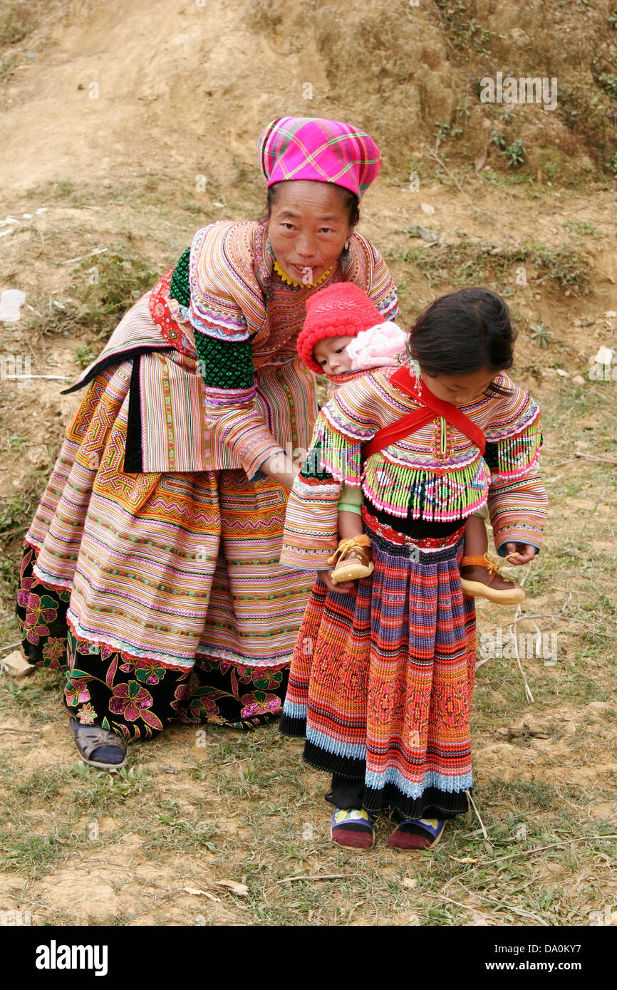 Flower Hmong woman helping her daughter to get her brother on the back ...