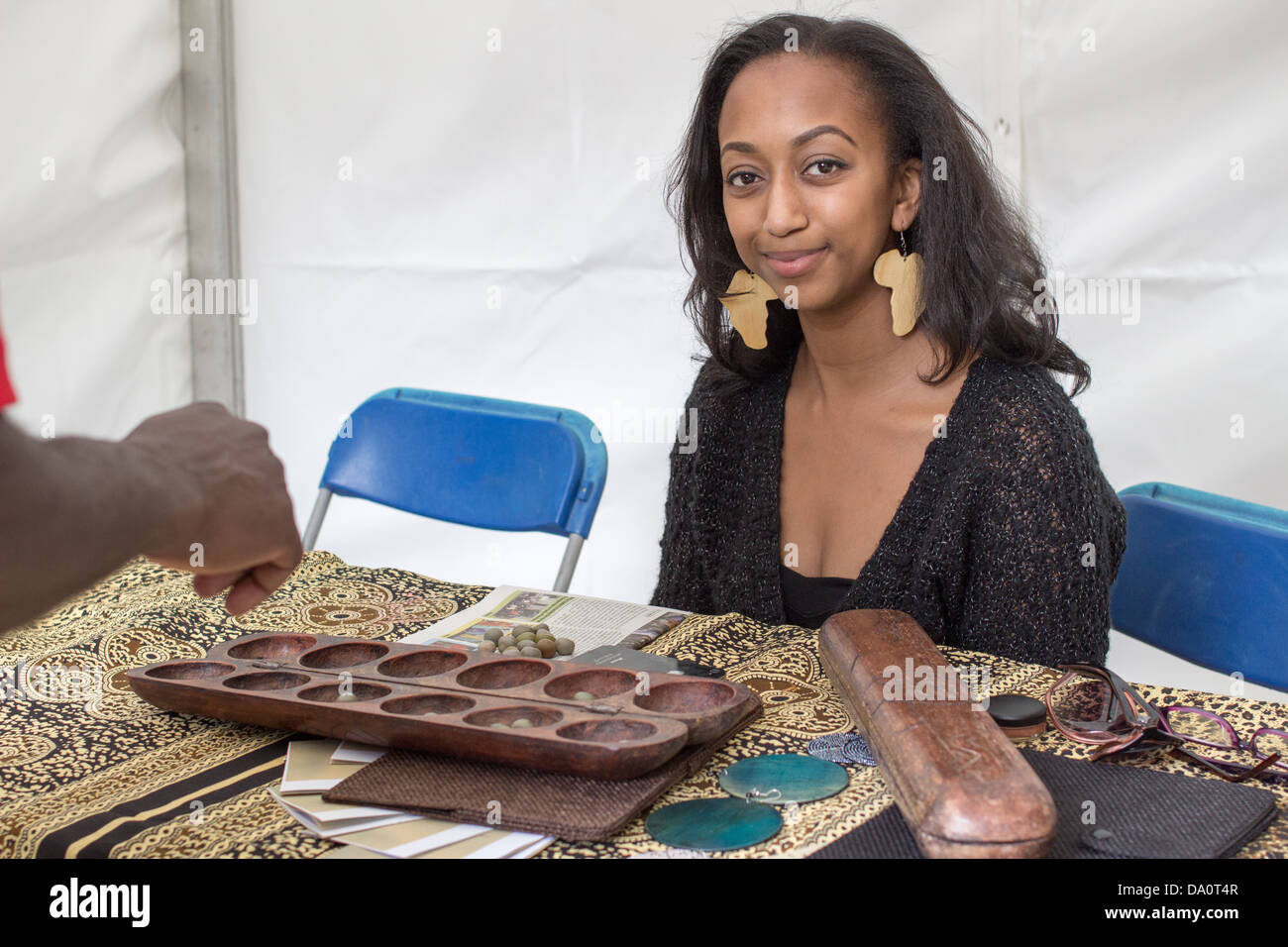 A woman plays a traditional African board game with a man. Africa Day ...
