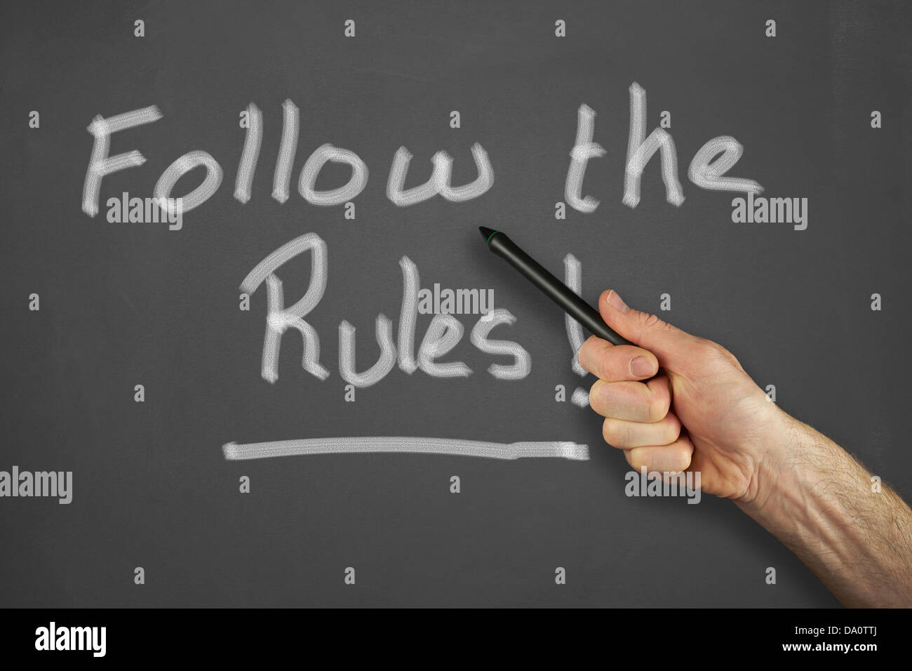Mans hand pointing to a rules message on a chalkboard Stock Photo - Alamy