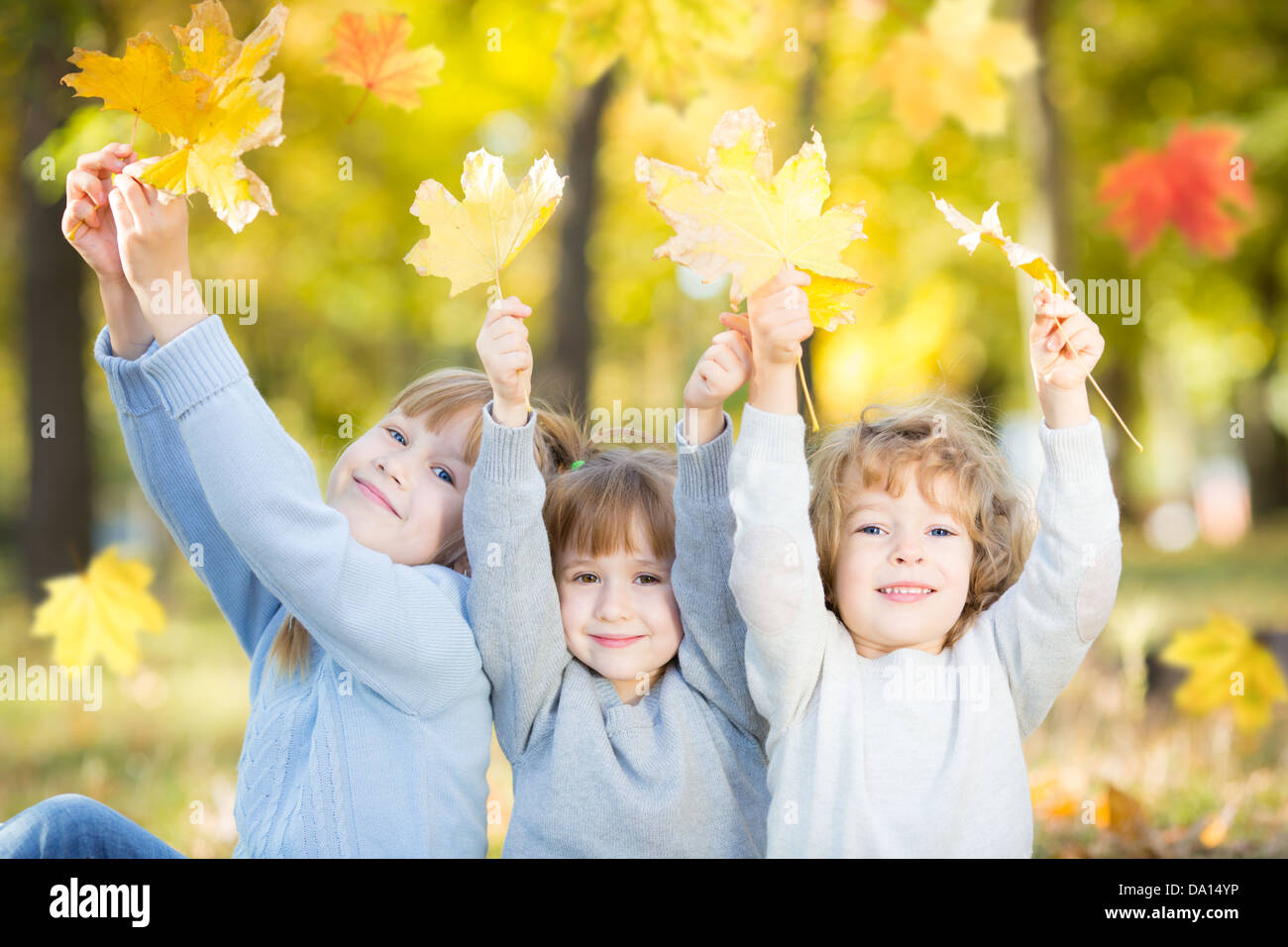 Happy children with maple leaves in autumn park Stock Photo - Alamy