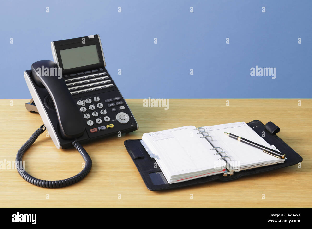 Telephone and agenda on wooden desk Stock Photo - Alamy