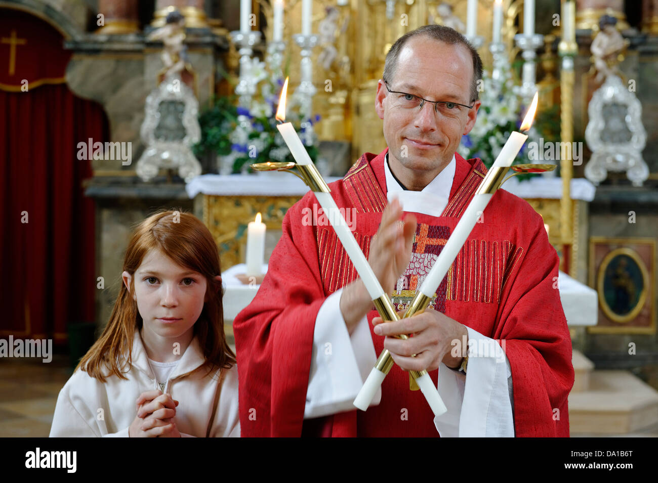 Germany, Bavaria, Priest holding candles for blessing of throats while ...