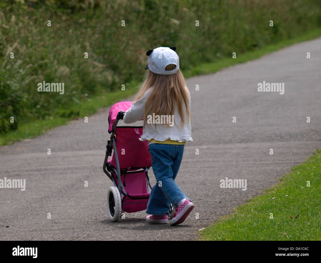 Young girl pushing a toy pram, Cornwall, UK 2013 Stock Photo - Alamy