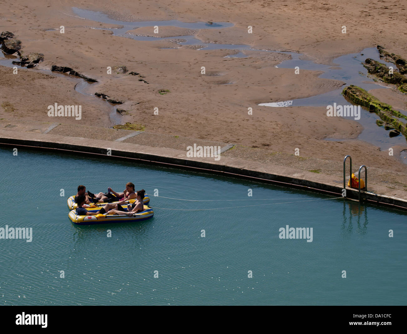 Two young couples relaxing in the sunshine in blow up boats in the ...