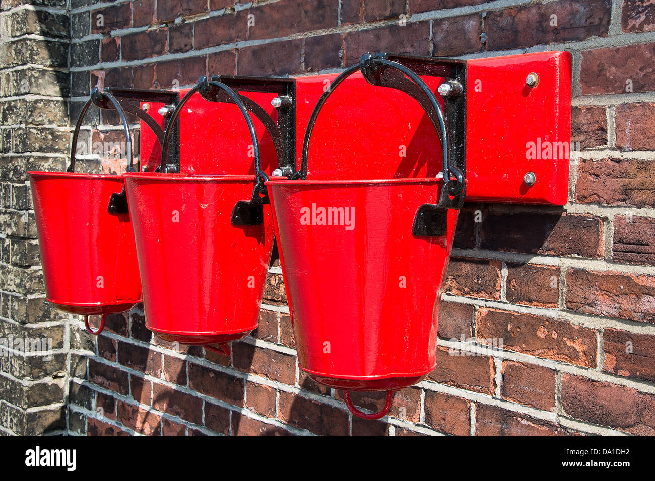 Red fire buckets wall mounted Stock Photo - Alamy