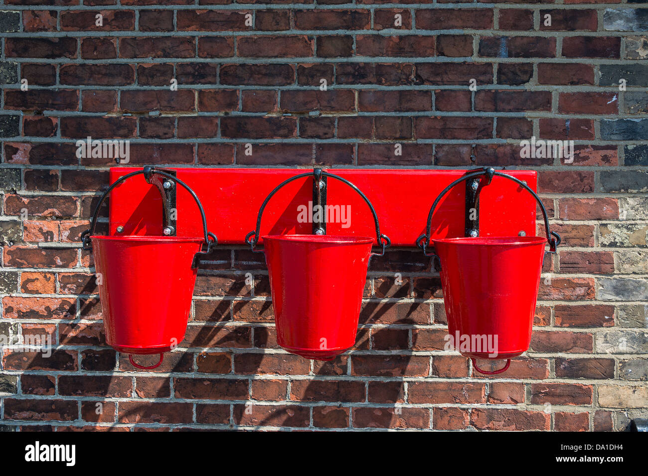 Red fire buckets wall mounted Stock Photo - Alamy