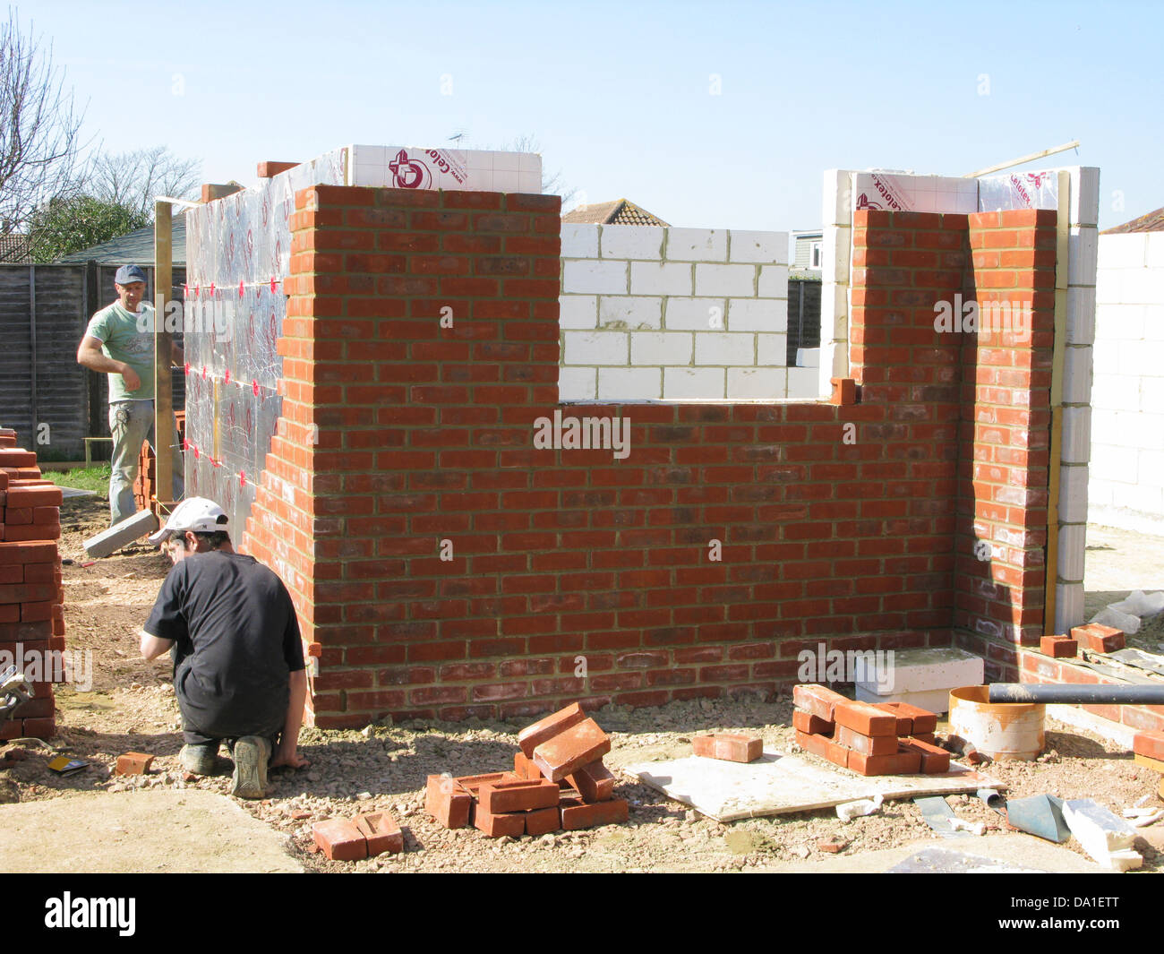 Builder / construction worker working on a brick wall cementing bricks ...