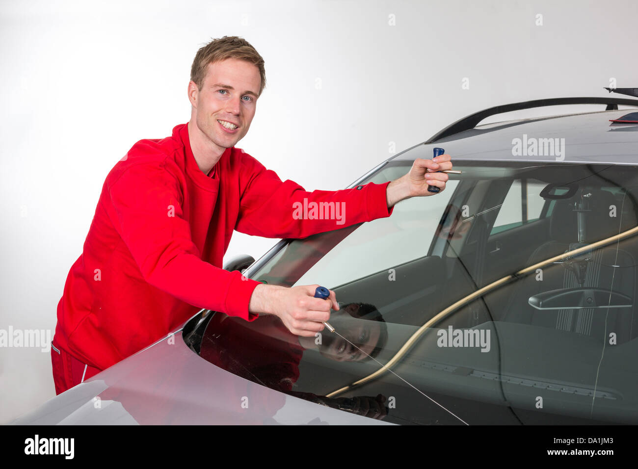 Glazier cutting adhesive of windscreen with a wire to replace ...