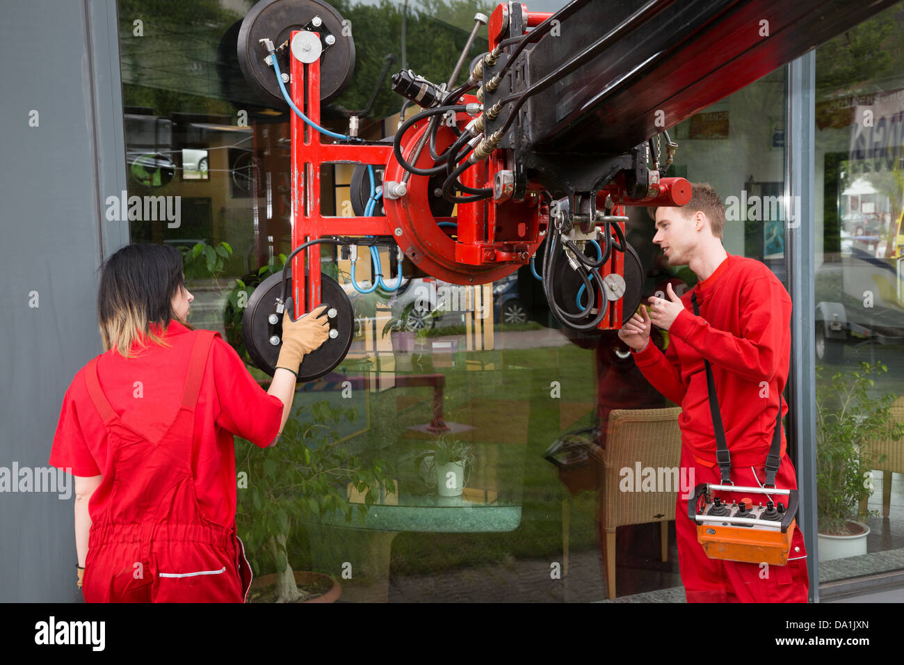 Glaziers operating a glass installation crane at glazier's workshop ...