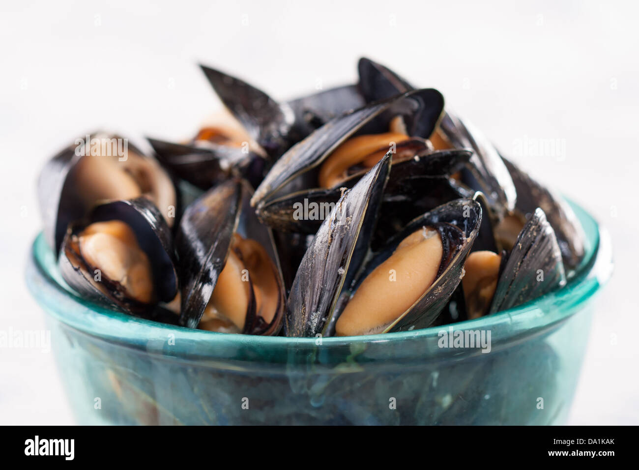 Steamed mussels on blue bowl over white background Stock Photo - Alamy