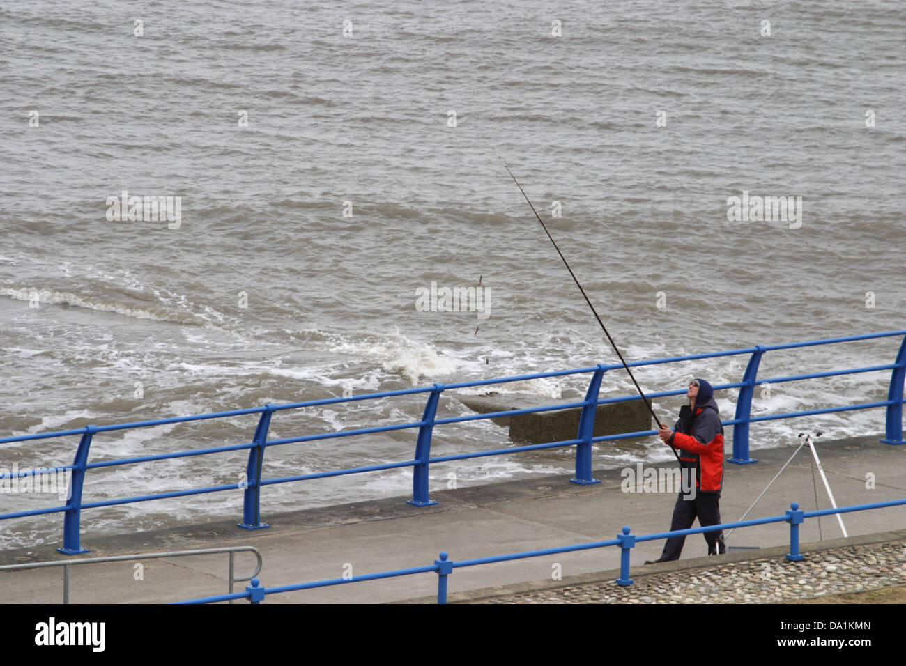 Solitary Fisherman fishing with his rod on the promenade at hendon ...