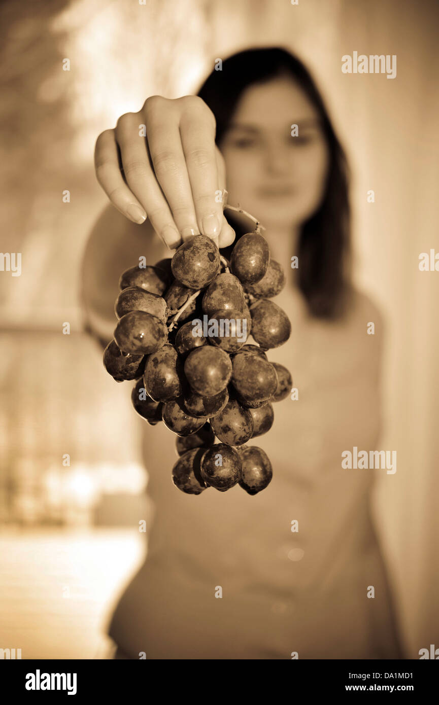 Young woman holding grapes in a stretched hand Stock Photo - Alamy
