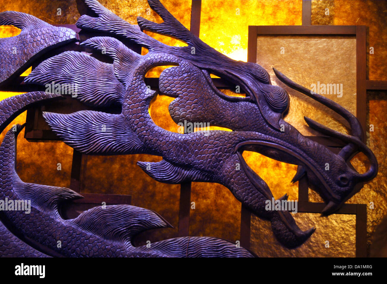 A carved Chinese dragon wall hanging, backed by an ember lighted ...