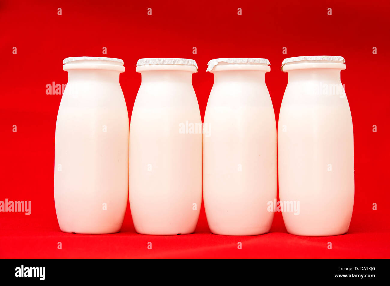 milk cans on a red background Stock Photo - Alamy