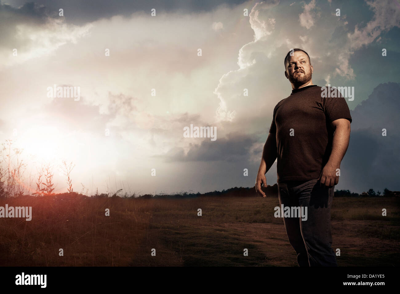 Man standing in front of sunset in open field Stock Photo - Alamy