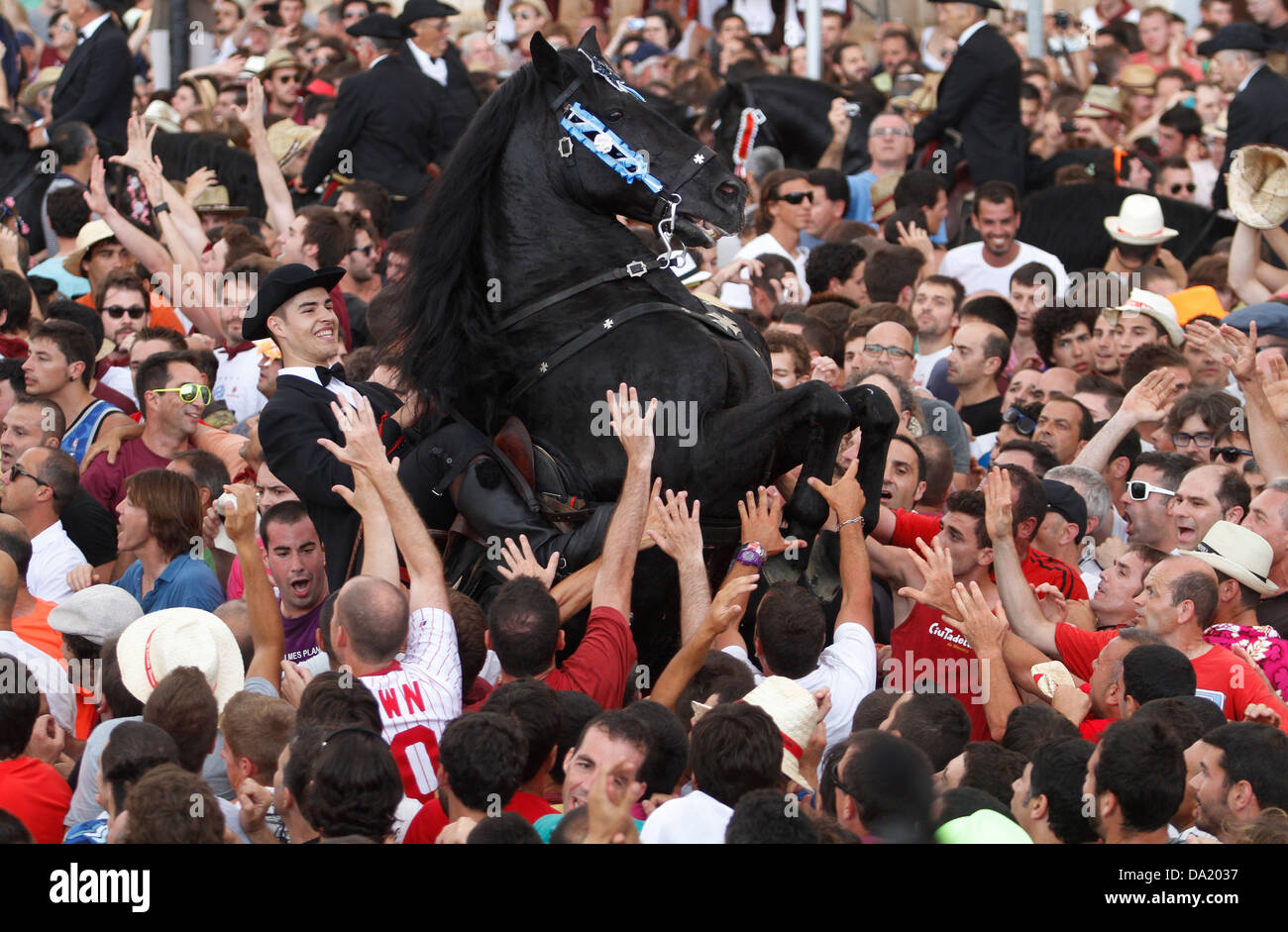 A rider rears up on his horse while surrounded by a cheering crowd ...