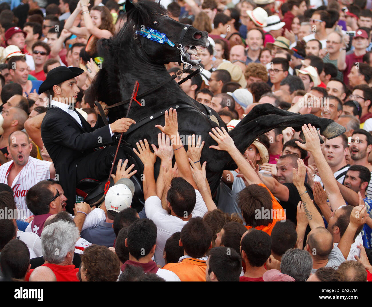 A rider rears up on his horse while surrounded by a cheering crowd ...