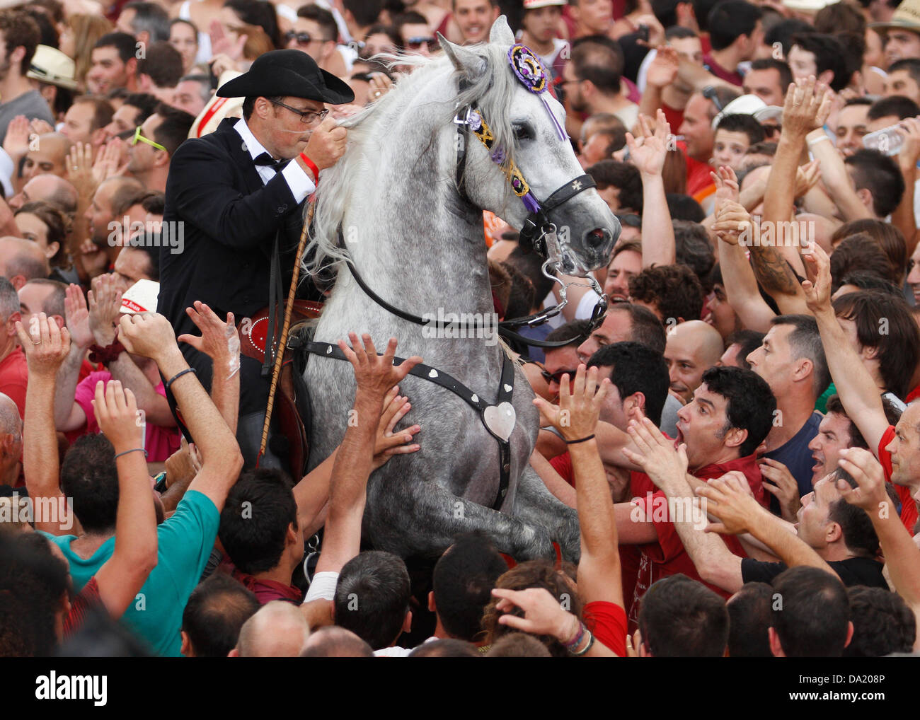 A rider rears up on his horse while surrounded by a cheering crowd ...