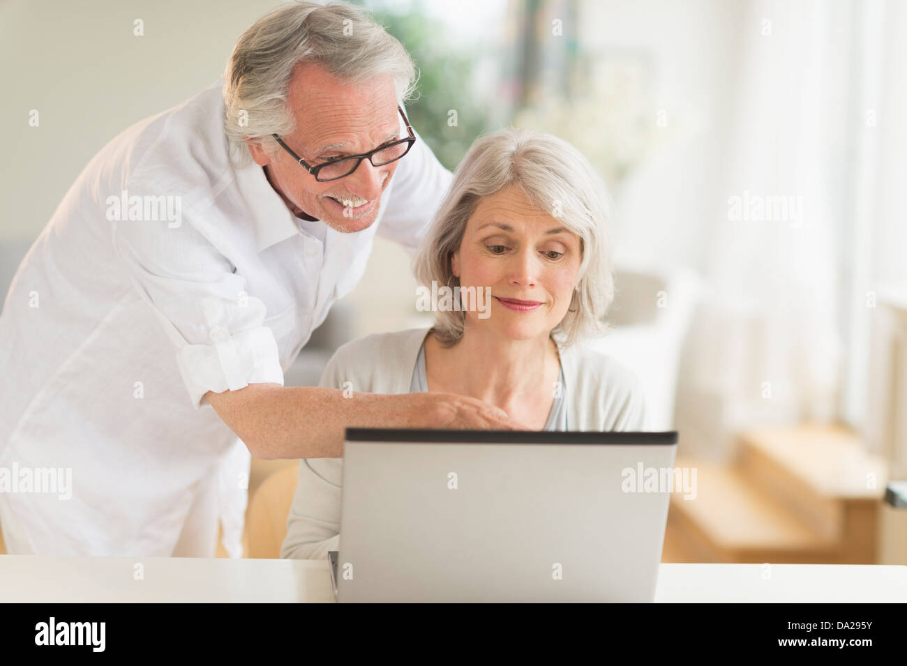 Happy senior couple using the laptop at the counter at home in the ...