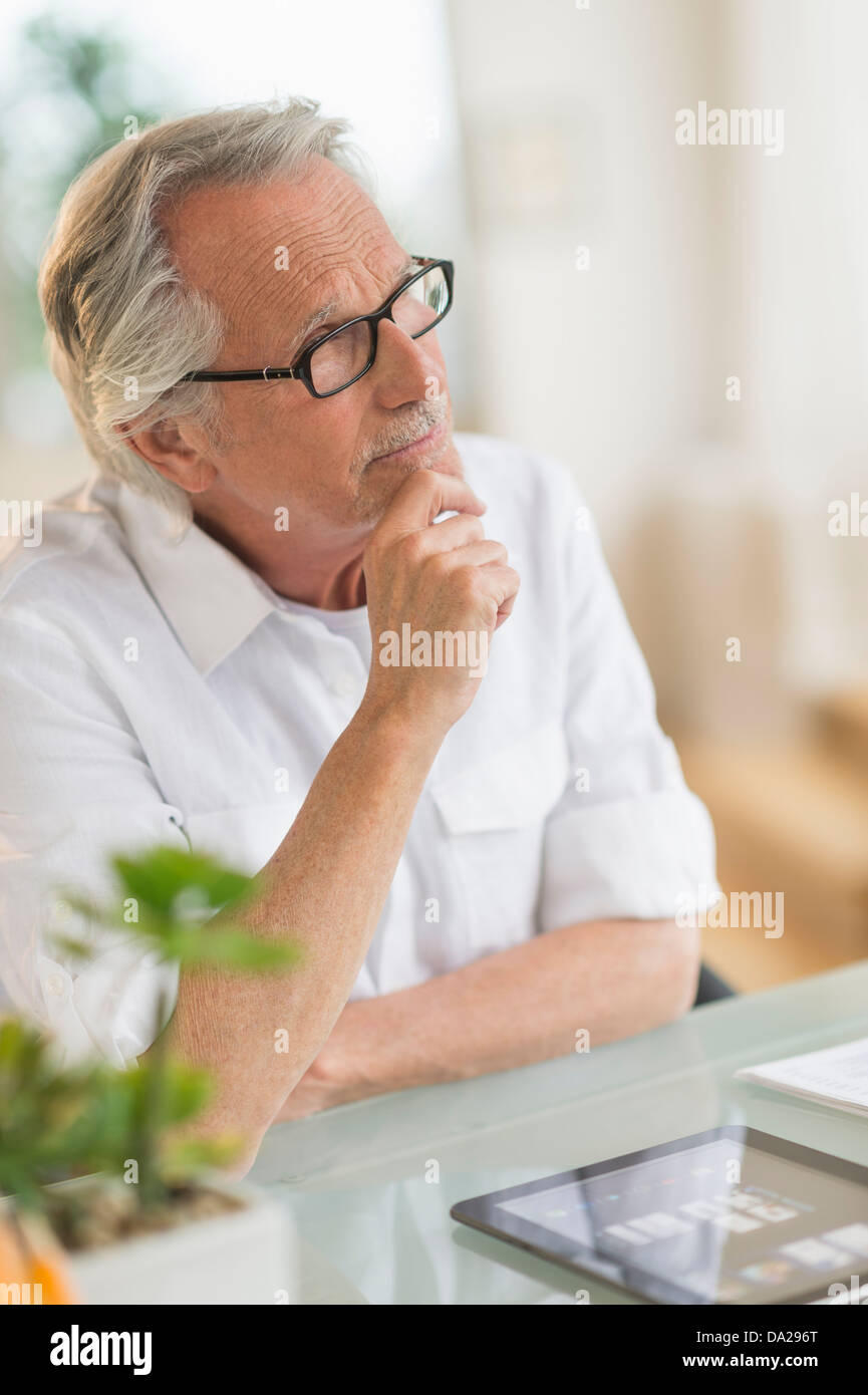 Portrait of senior man thinking at desk Stock Photo - Alamy