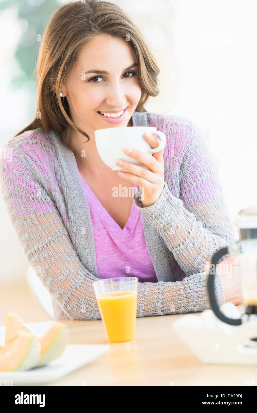 Portrait of young woman drinking tea at table Stock Photo - Alamy